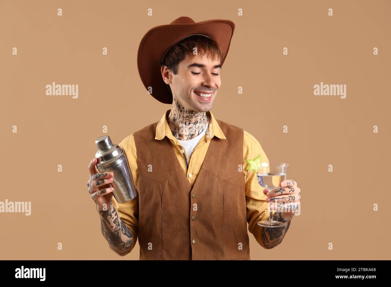 Young male bartender dressed as cowboy with shaker and glass of ...