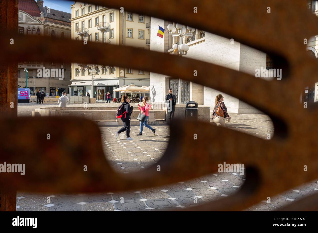 A female adult is striding across a public plaza surrounded by classic ...