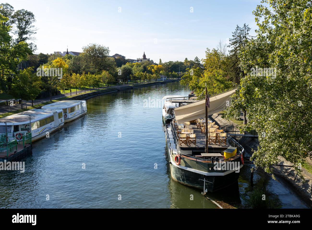 A scenic aerial view of a river with multiple boats docked in a line ...