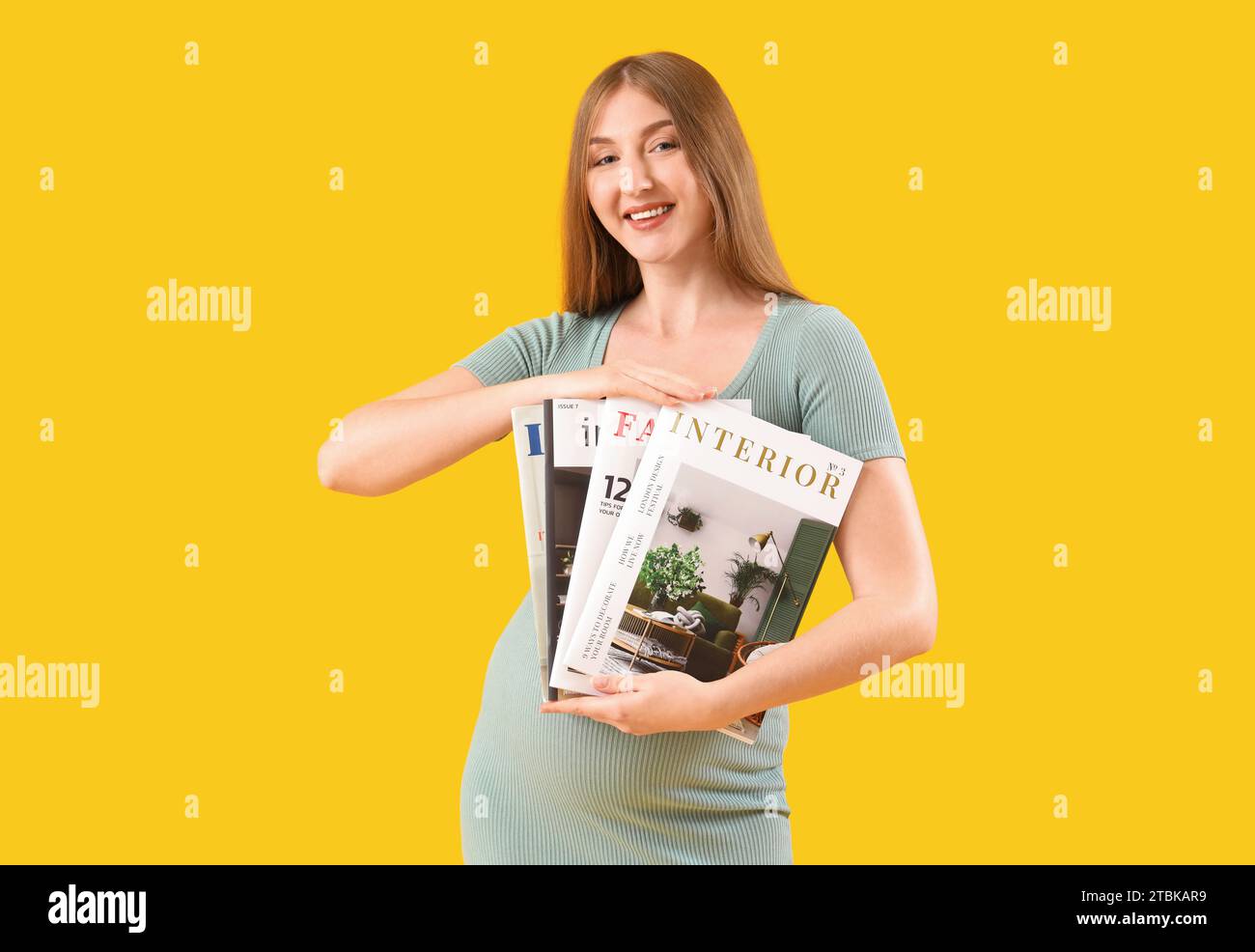 Beautiful young happy pregnant woman with magazines on yellow ...