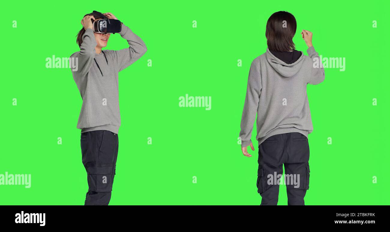 Young guy enjoys virtual reality device in studio with greenscreen ...