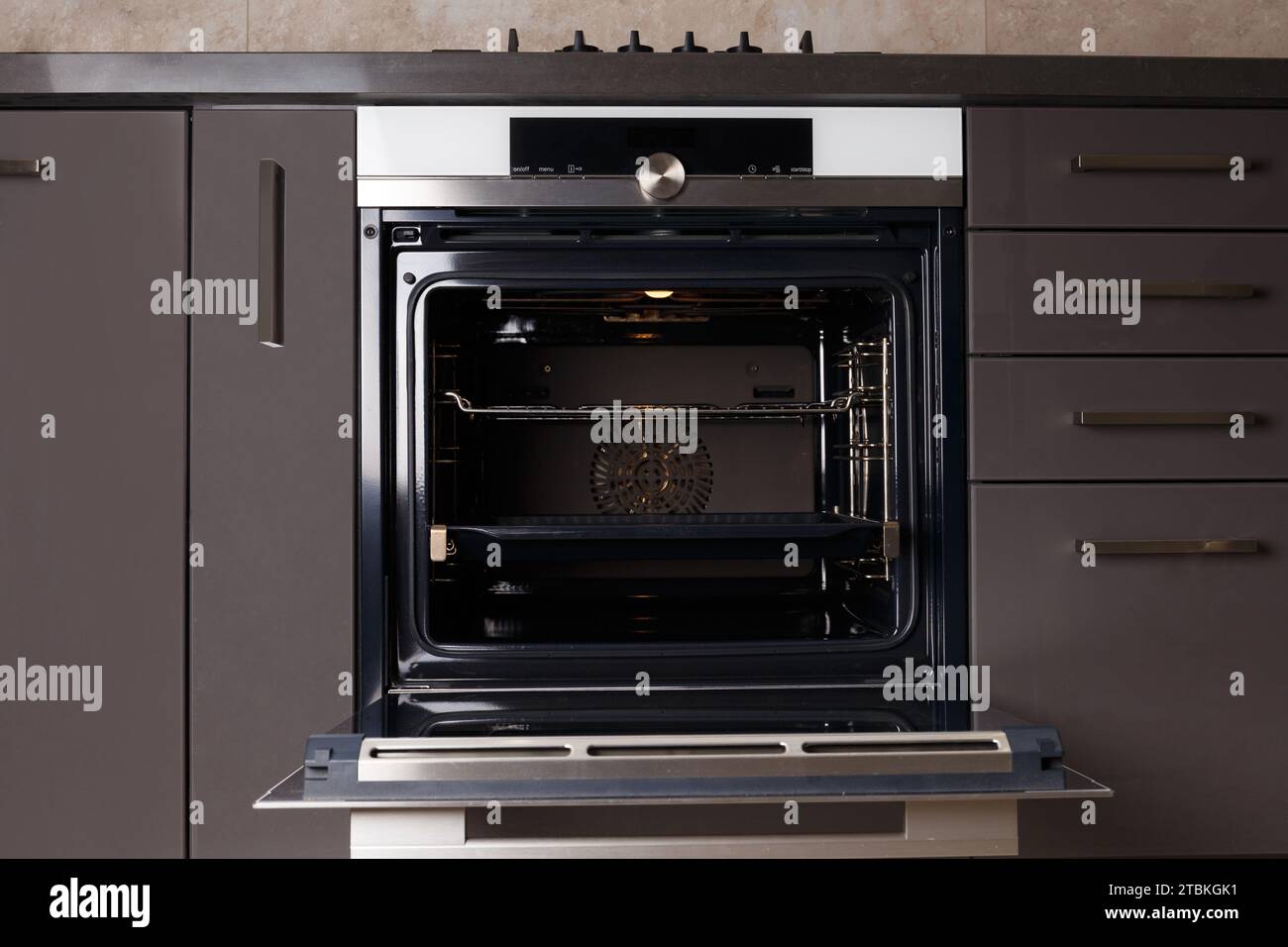Built-in electric oven with an open door in the interior of the kitchen ...