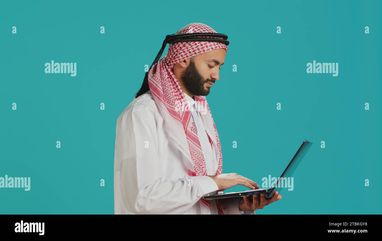 Person using laptop touchpad in studio, dressed in traditional muslim ...