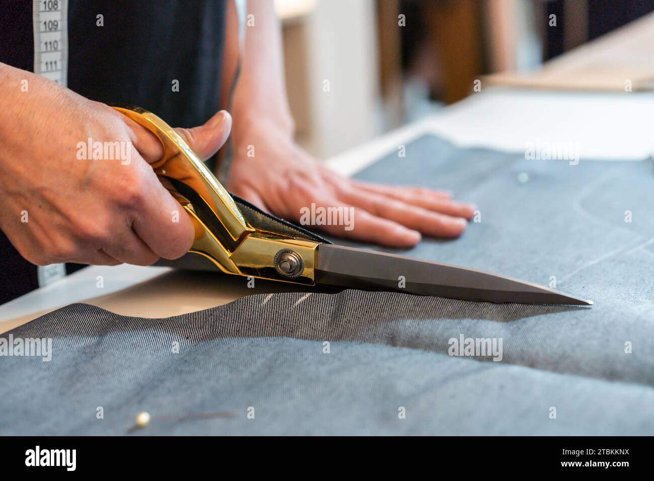 Close-up of fashion designer hands using scissors to cut textile at ...