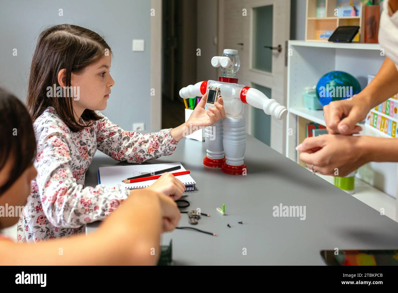 Female student holding solar panel over recycled toy robot in a ...