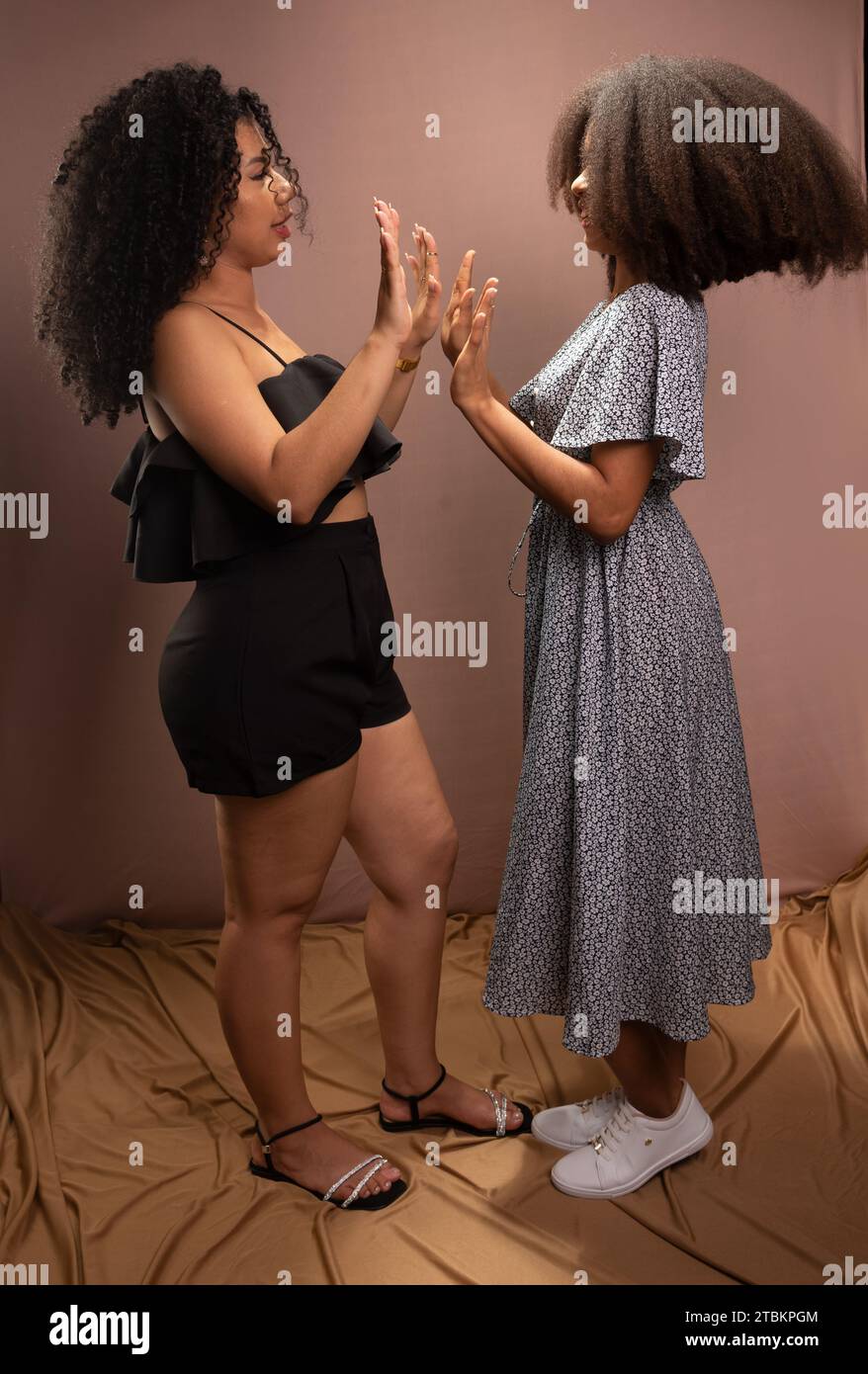Two young, happy friends touching each other's hands, standing ...