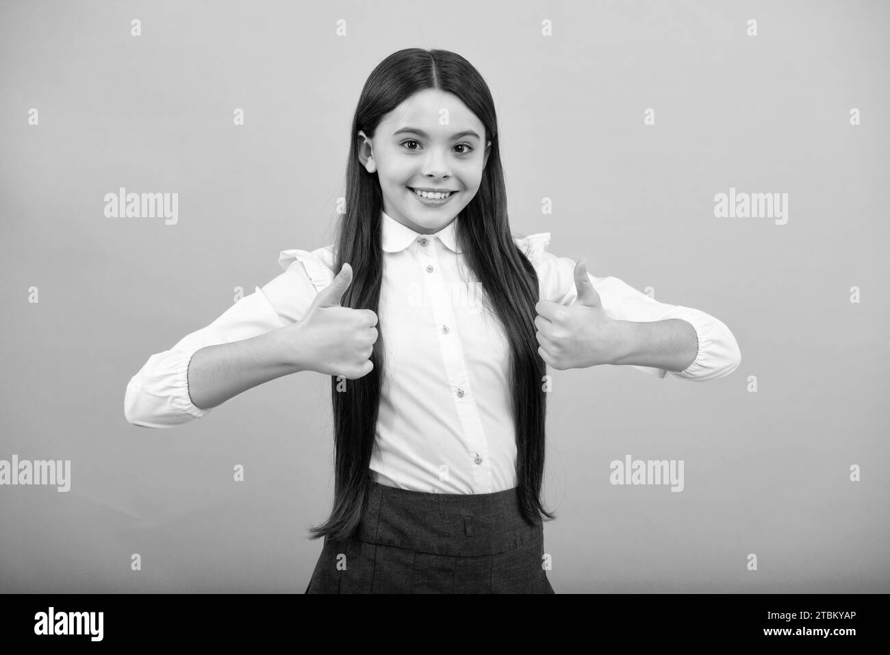Little schoolgirl student. Portrait of a happy casual teenager child girl showing thumbs up and ...