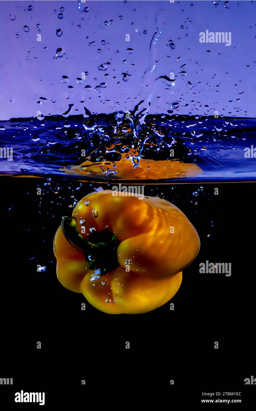 bell peppers on a dark background are dropped into the water causing a ...