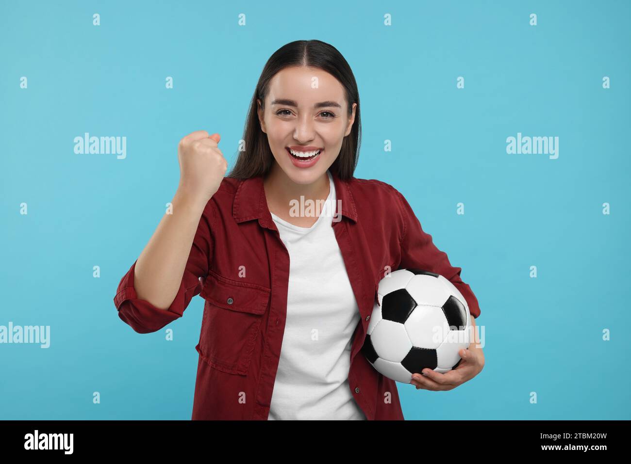 Happy fan holding soccer ball and celebrating on light blue background ...