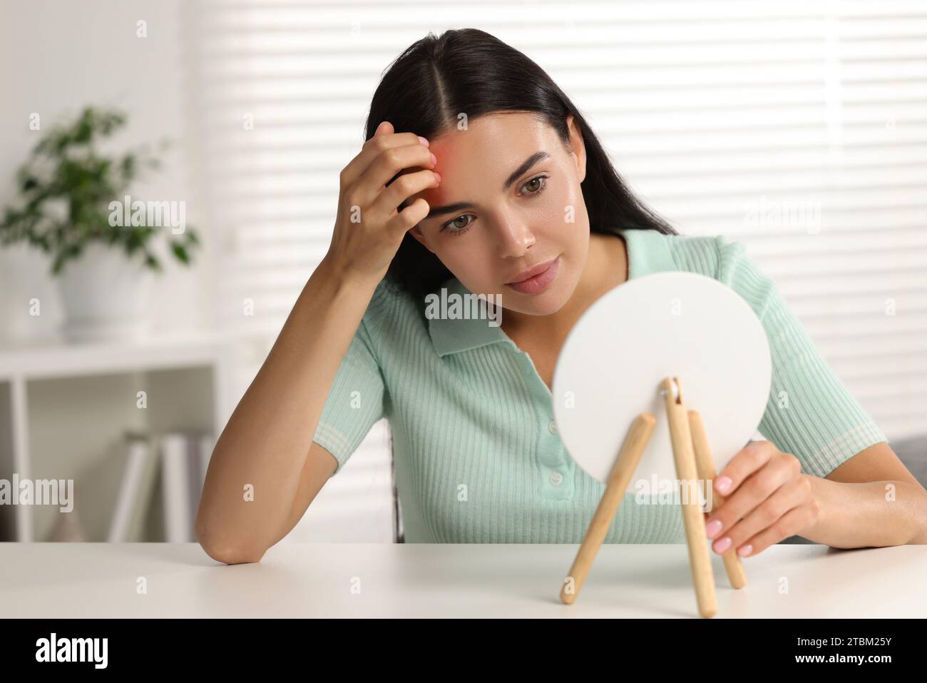 Suffering from allergy. Young woman looking in mirror and scratching ...