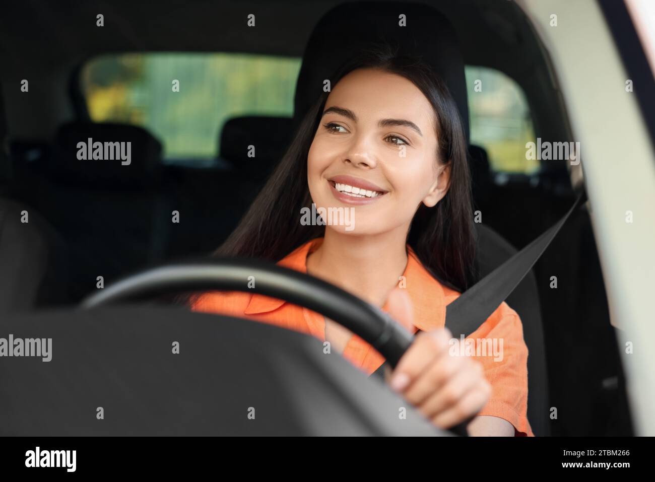 Enjoying trip. Happy young woman driving her car, view through ...