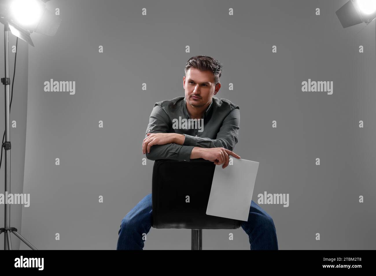 Casting call. Man with script sitting on chair against grey background ...