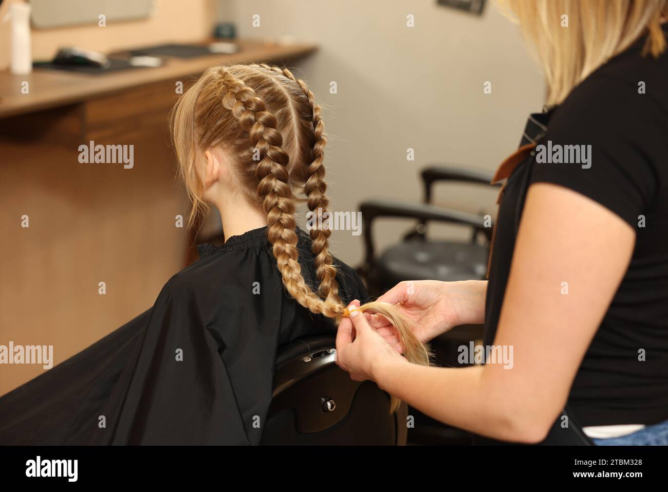 Professional hairdresser braiding girl's hair in beauty salon Stock ...