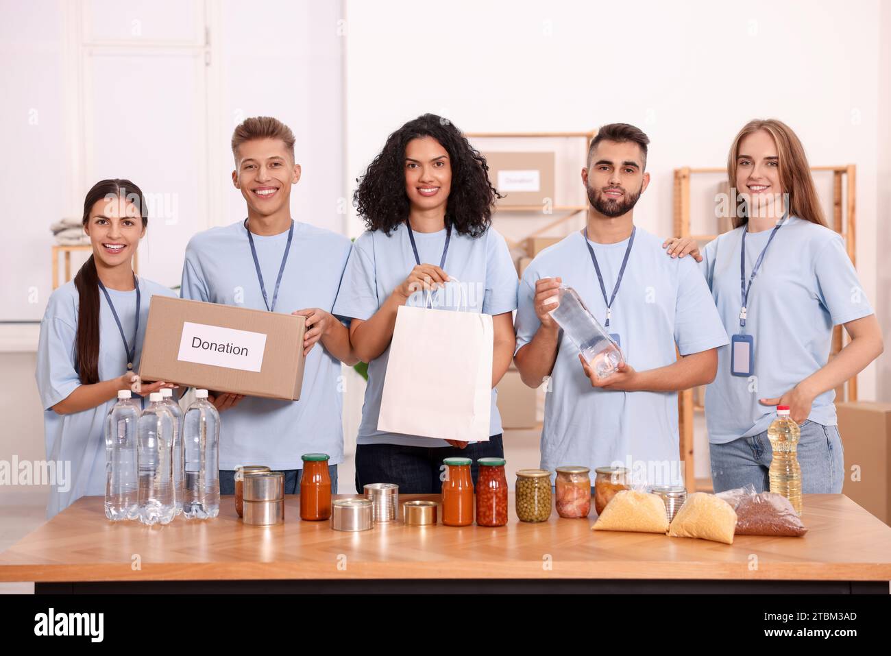 Portrait of volunteers with donation box, paper bag and food products ...