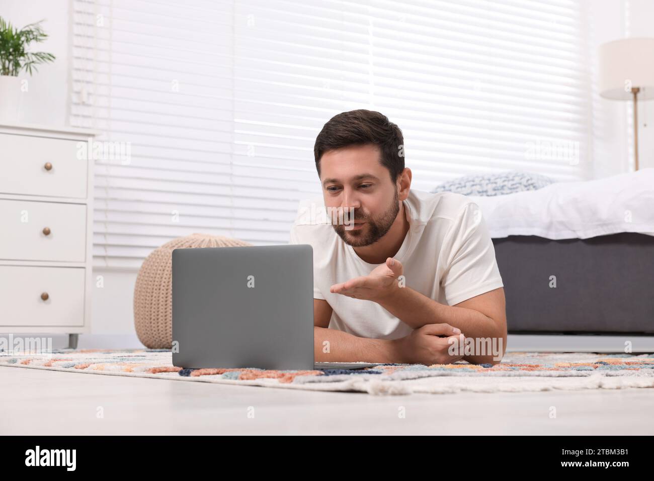 Man blowing kiss during video chat via laptop at home. Long-distance ...