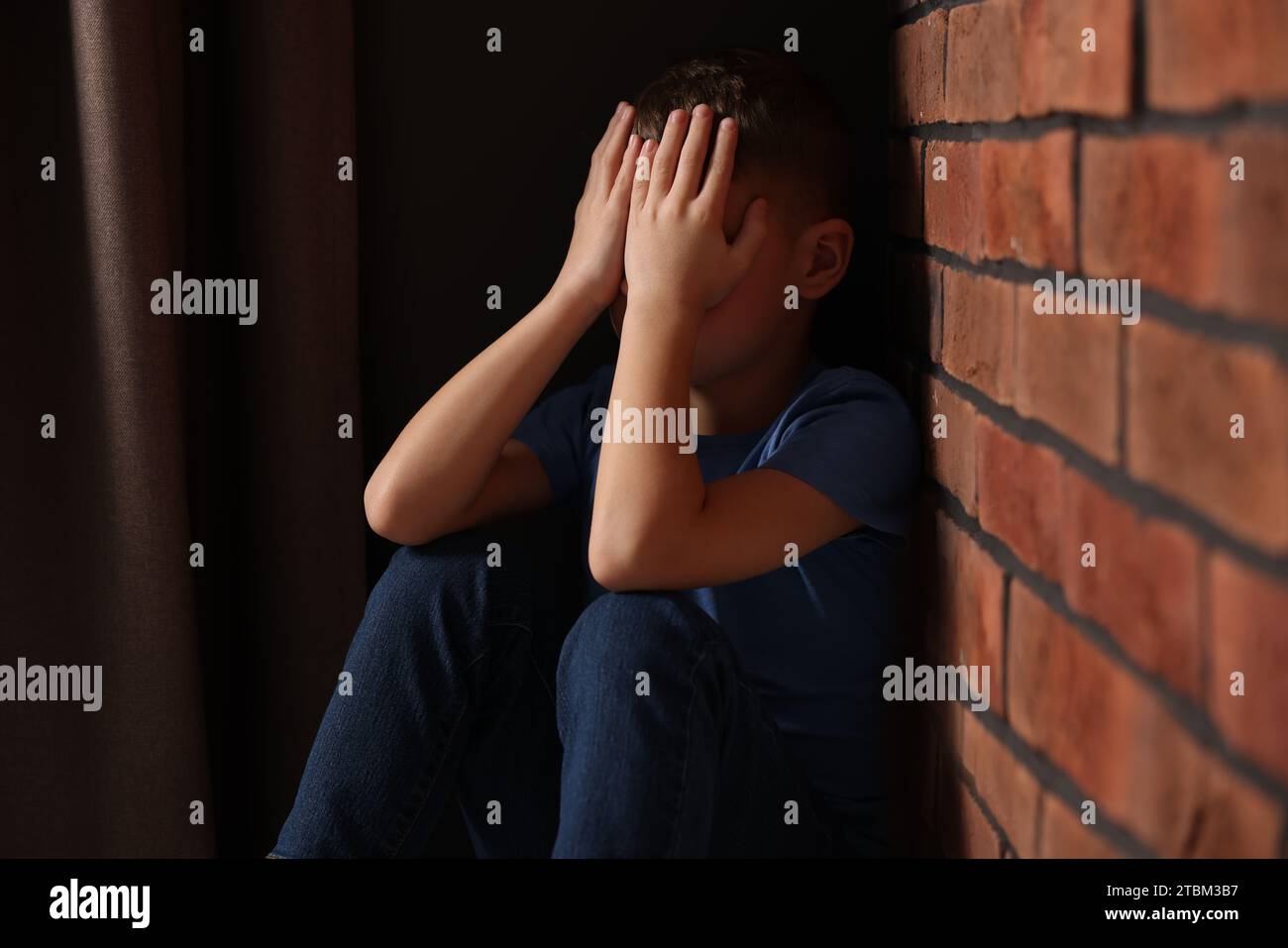 Child abuse. Upset boy near brick wall indoors Stock Photo - Alamy