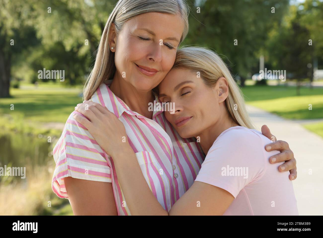 Family portrait of mother and daughter hugging in park Stock Photo - Alamy