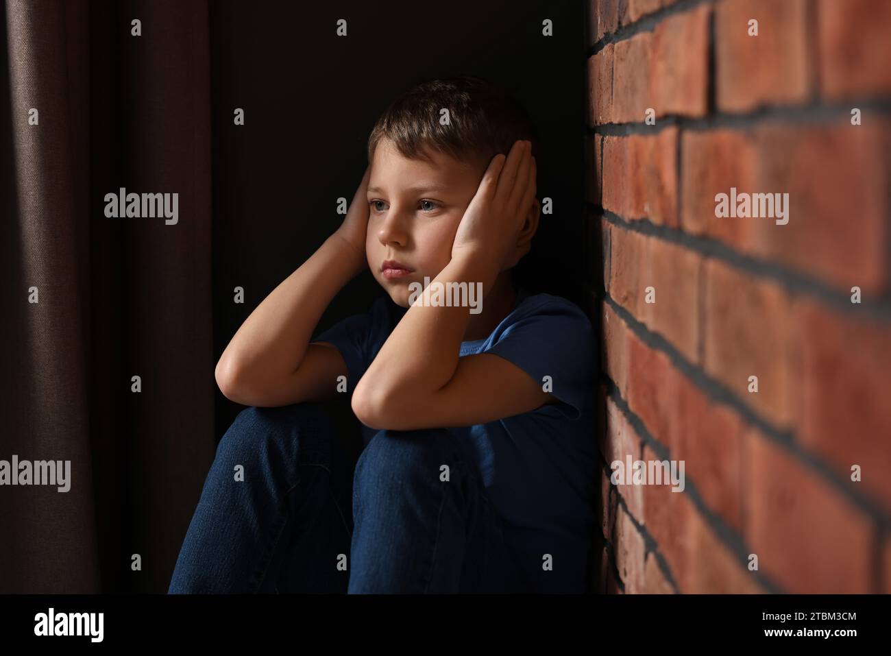 Child abuse. Upset boy near brick wall indoors Stock Photo - Alamy
