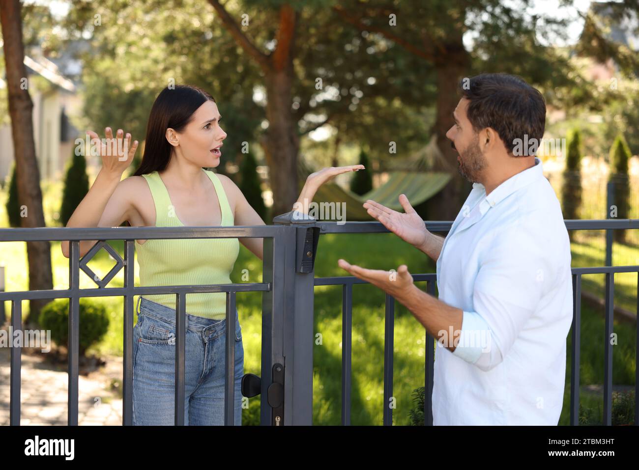 Emotional neighbours having argument near fence outdoors Stock Photo ...