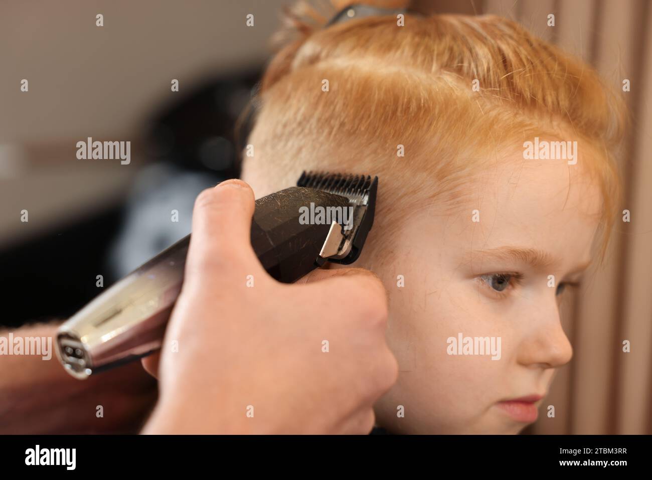 Professional hairdresser cutting boy's hair in beauty salon, closeup ...