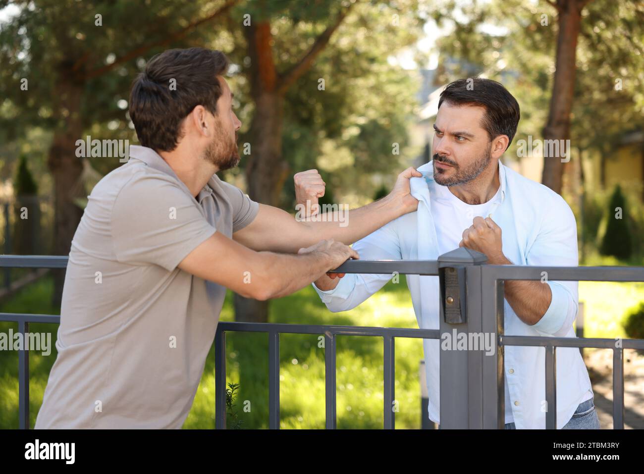 Angry neighbours having argument near fence outdoors Stock Photo - Alamy