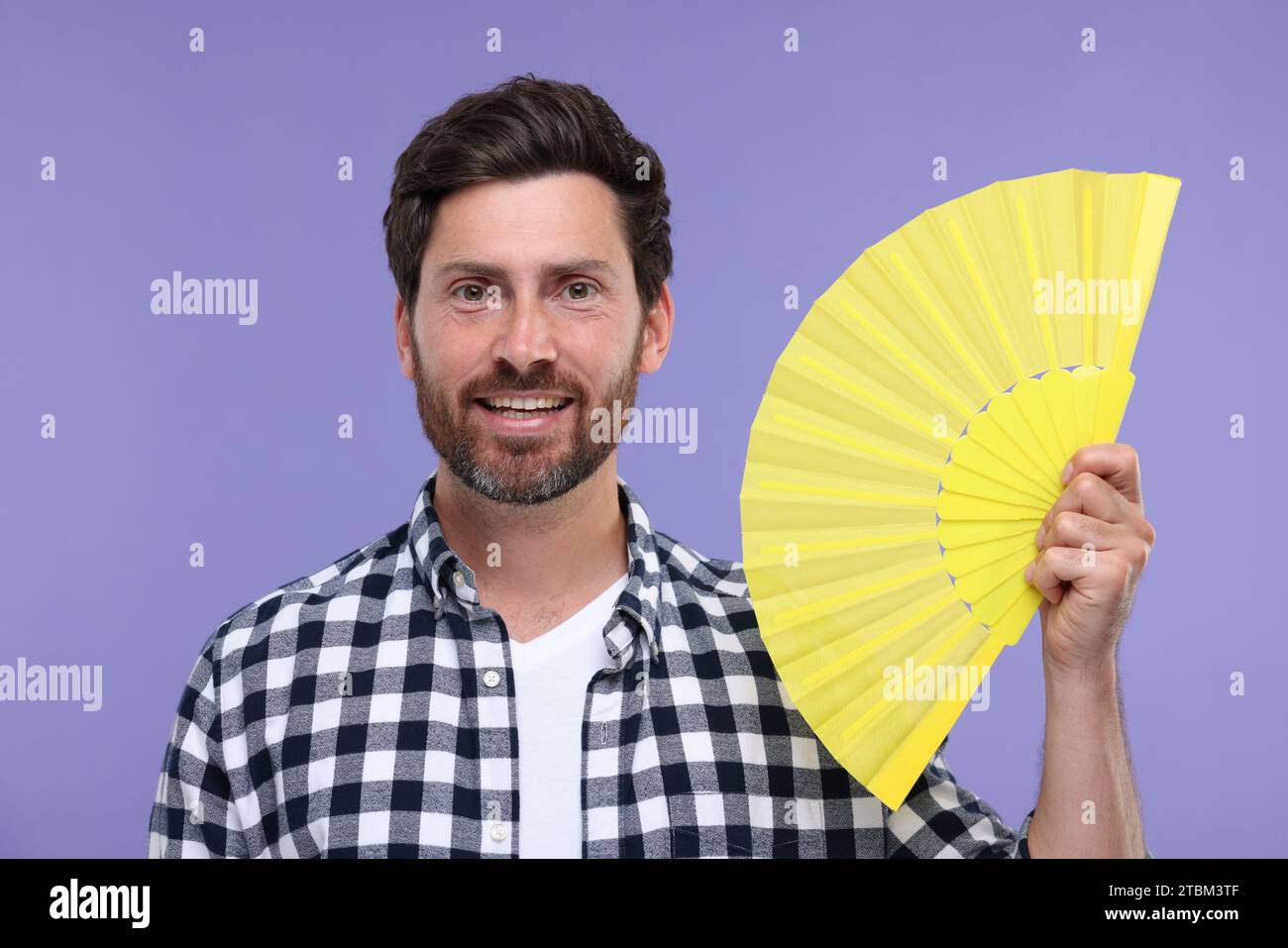 Happy man holding hand fan on purple background Stock Photo - Alamy
