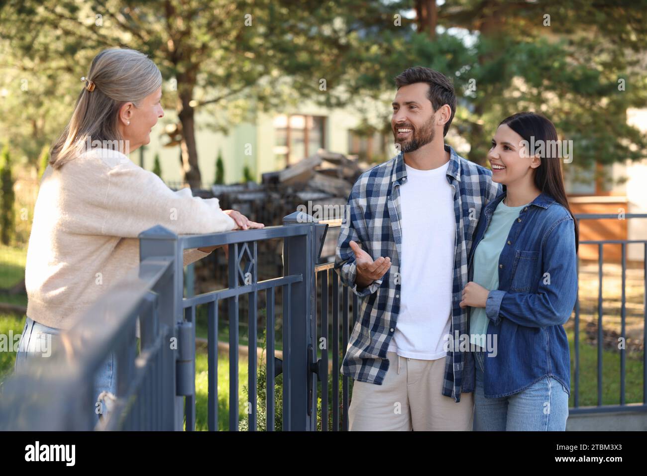 Friendly relationship with neighbours. Happy young couple talking to ...