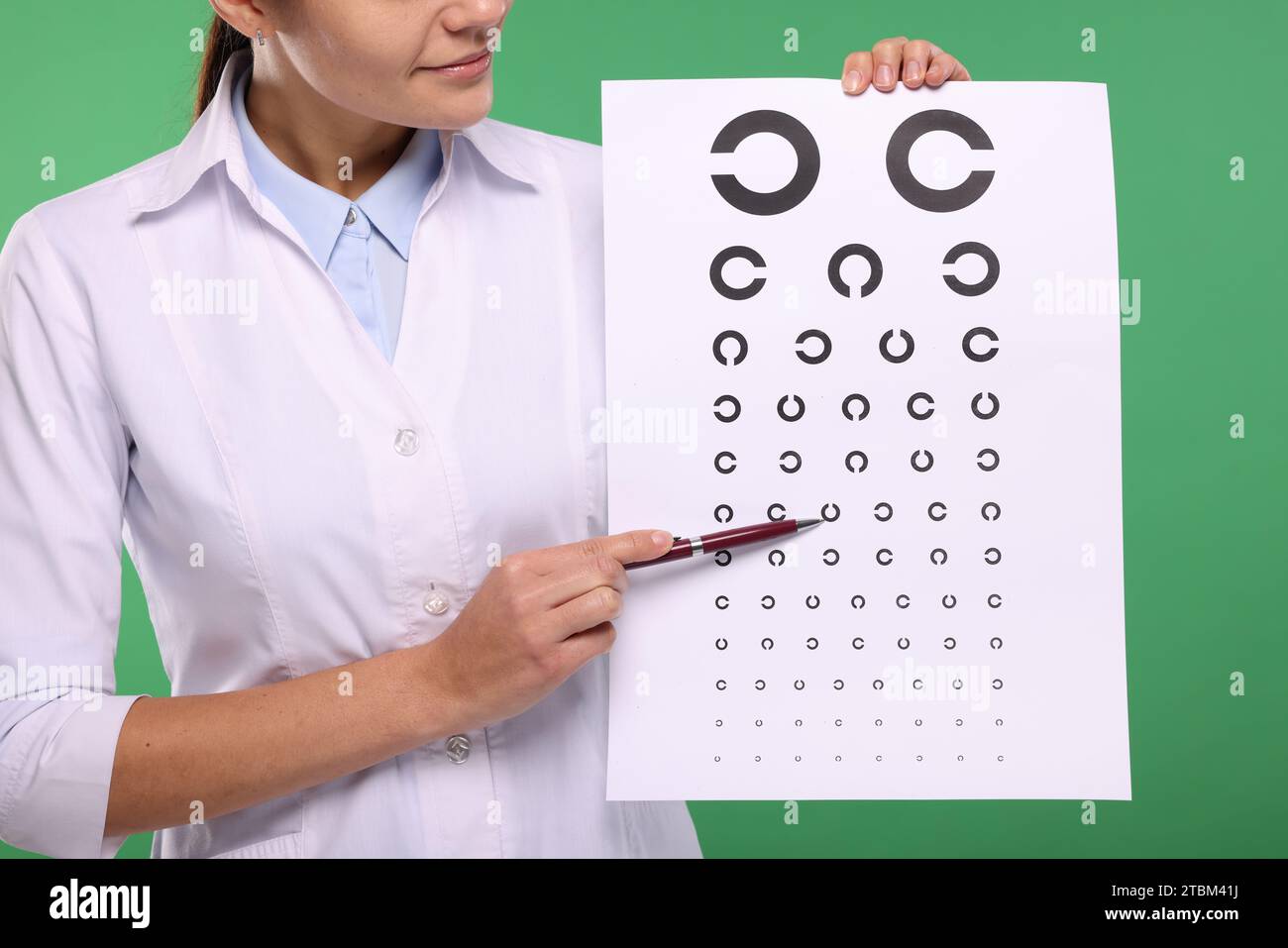 Ophthalmologist pointing at vision test chart on green background ...