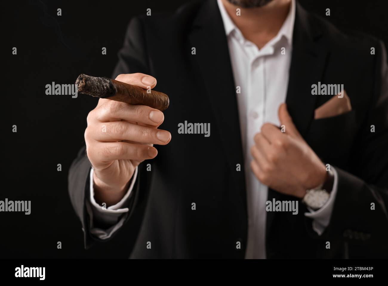 Man in elegant suit smoking cigar on black background, closeup Stock Photo - Alamy