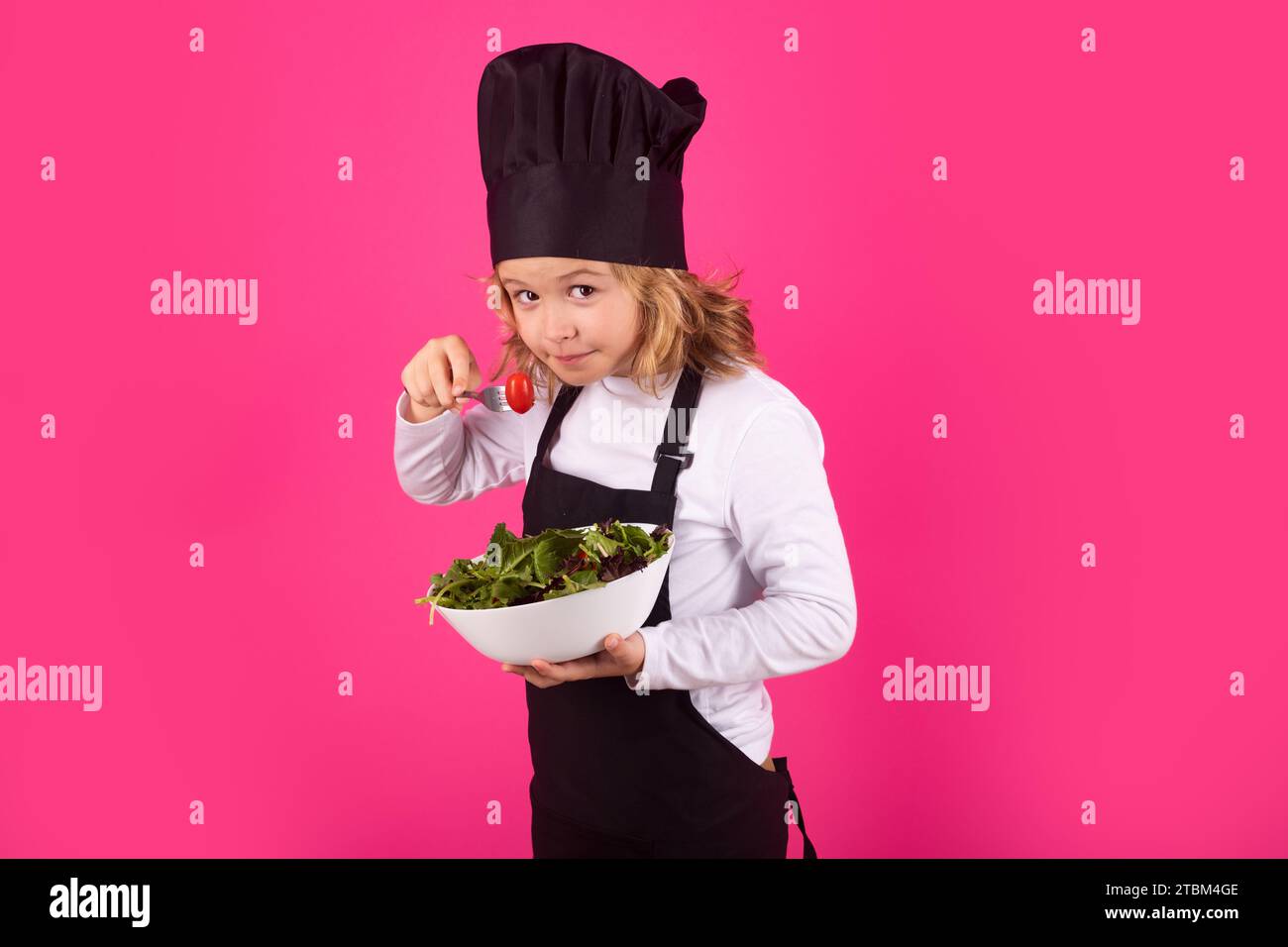 Kid cook hold plate with vegetables and fork with tomato. Child chef ...