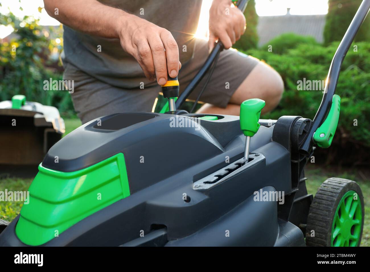 Man with screwdriver fixing lawn mower in garden, closeup Stock Photo ...