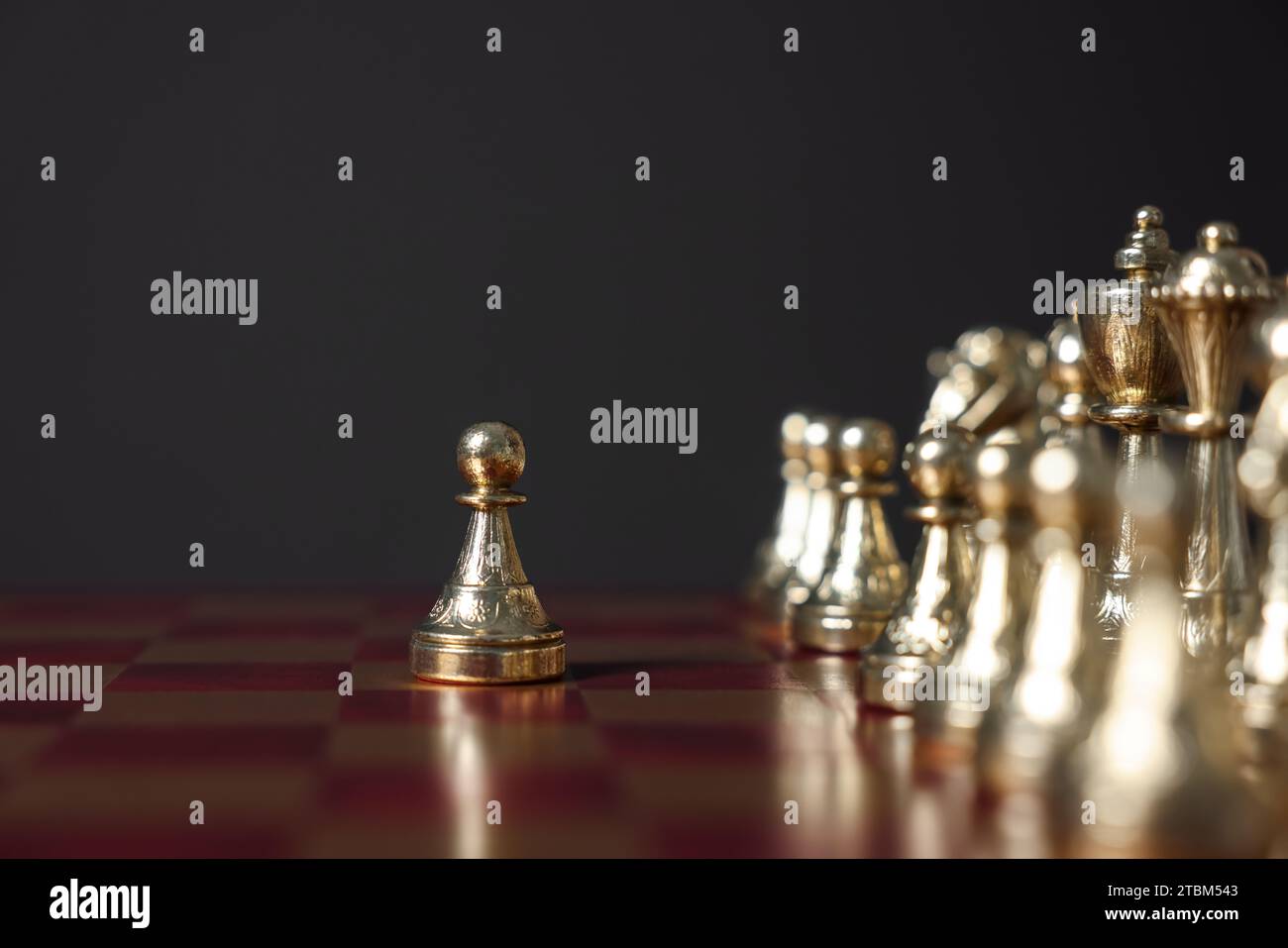 Golden chess pieces on checkerboard against dark background Stock Photo ...