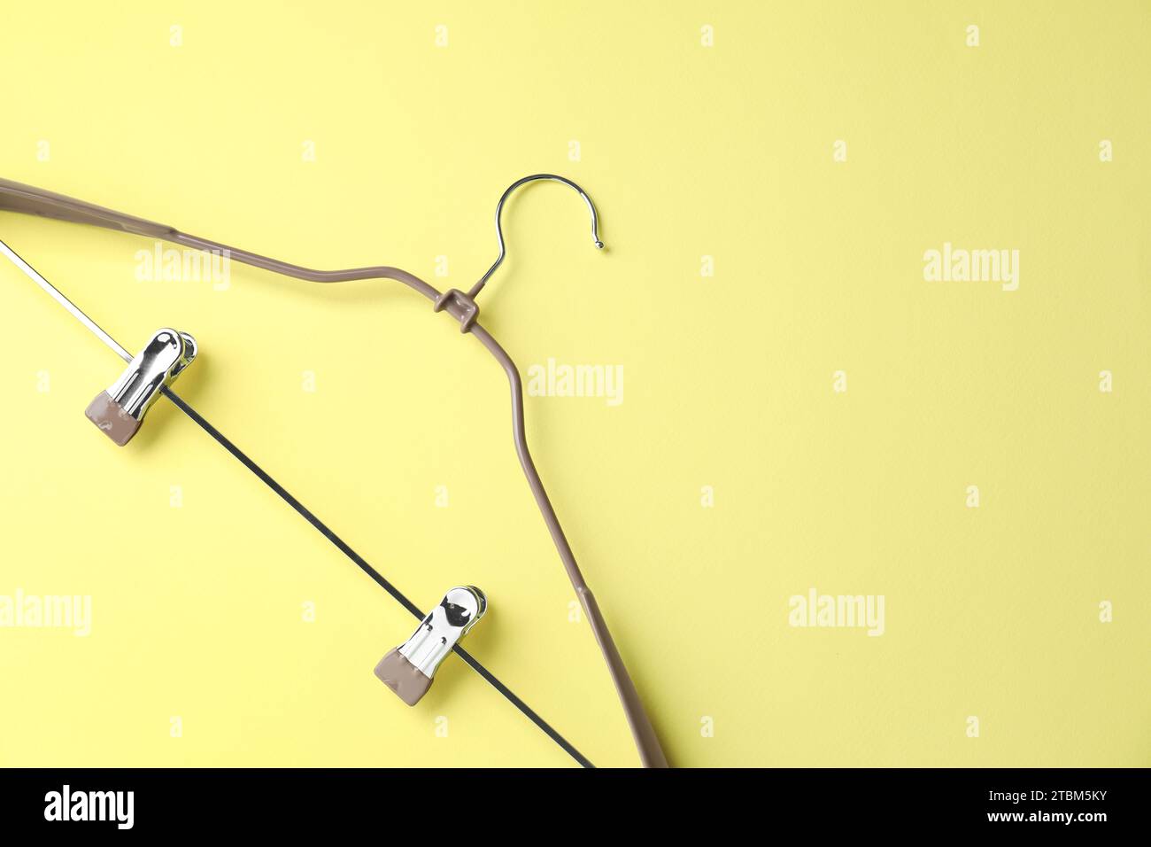 Empty hanger with clips on yellow background, top view. Space for text ...