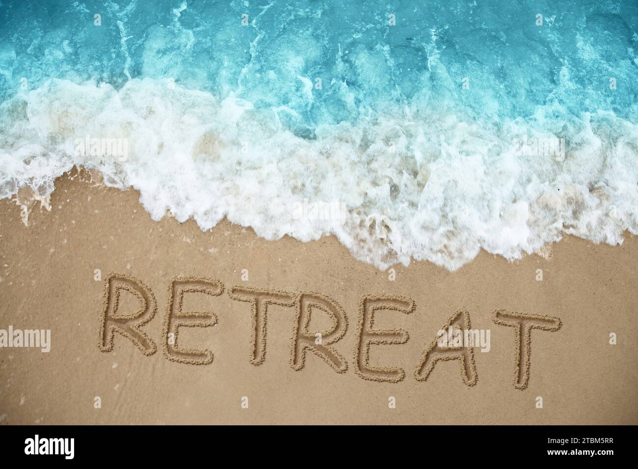 Word Retreat drawn on sand near sea, above view Stock Photo - Alamy