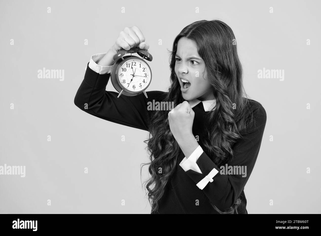 Teenager child hold clock isolated on yellow studio background ...