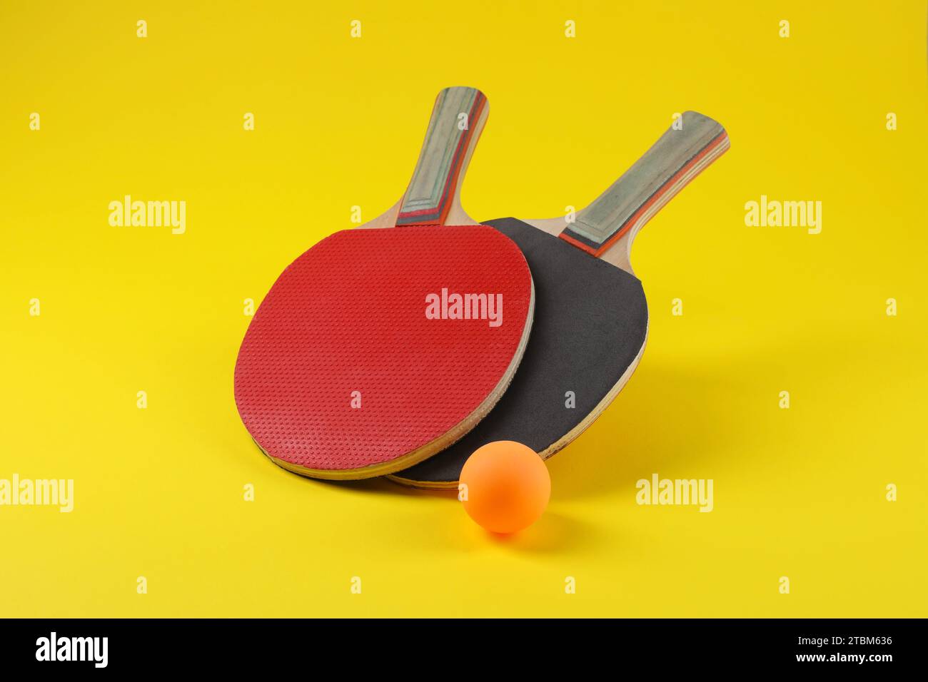 Ping pong ball and rackets on yellow background Stock Photo - Alamy