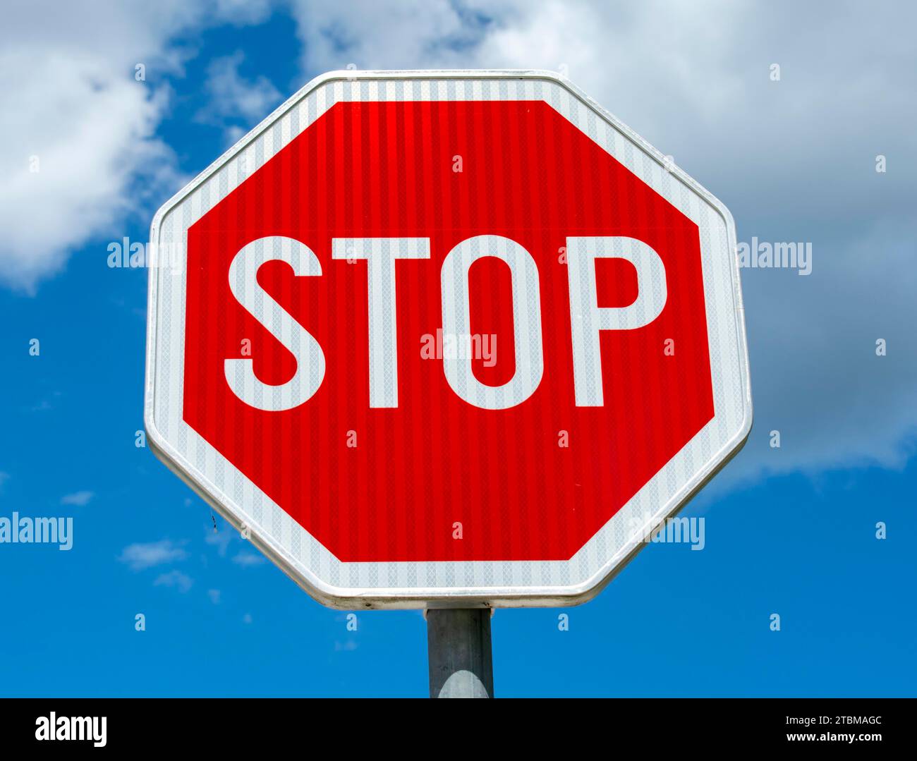 Red octagonal Stop sign on a metal pole with cloudy sky in the ...