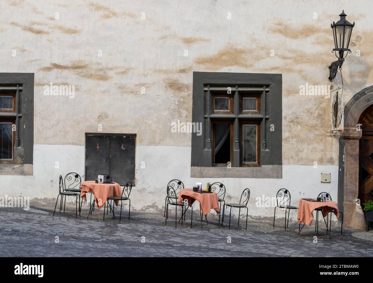 Old dark antique window with black round tables and metal chairs on the ...