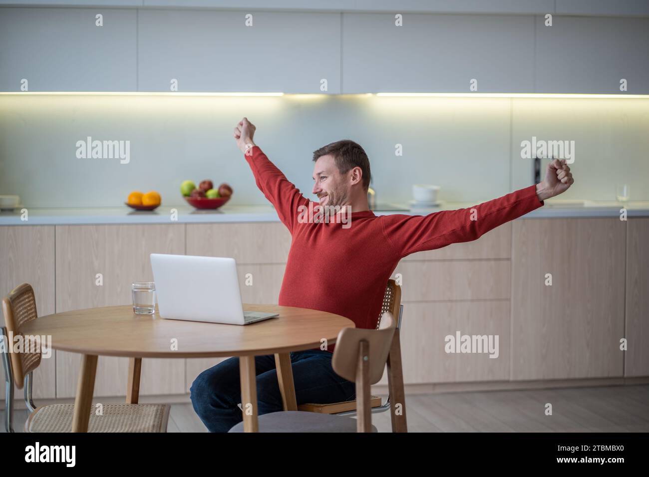 Smiling pleased happy man freelancer stretching arms in satisfaction ...