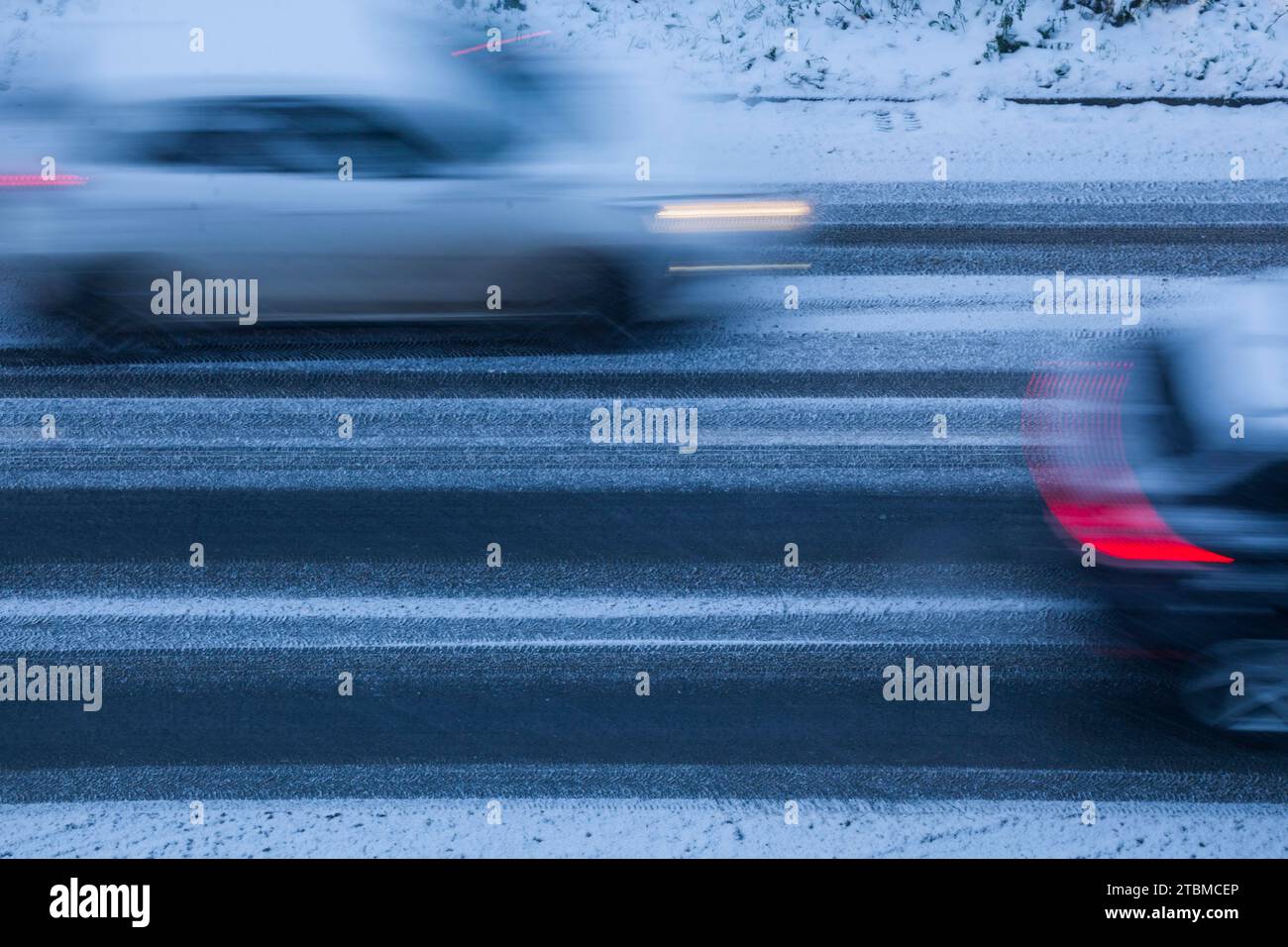Snow-covered carriageway and blurred moving cars at dawn, road, top ...