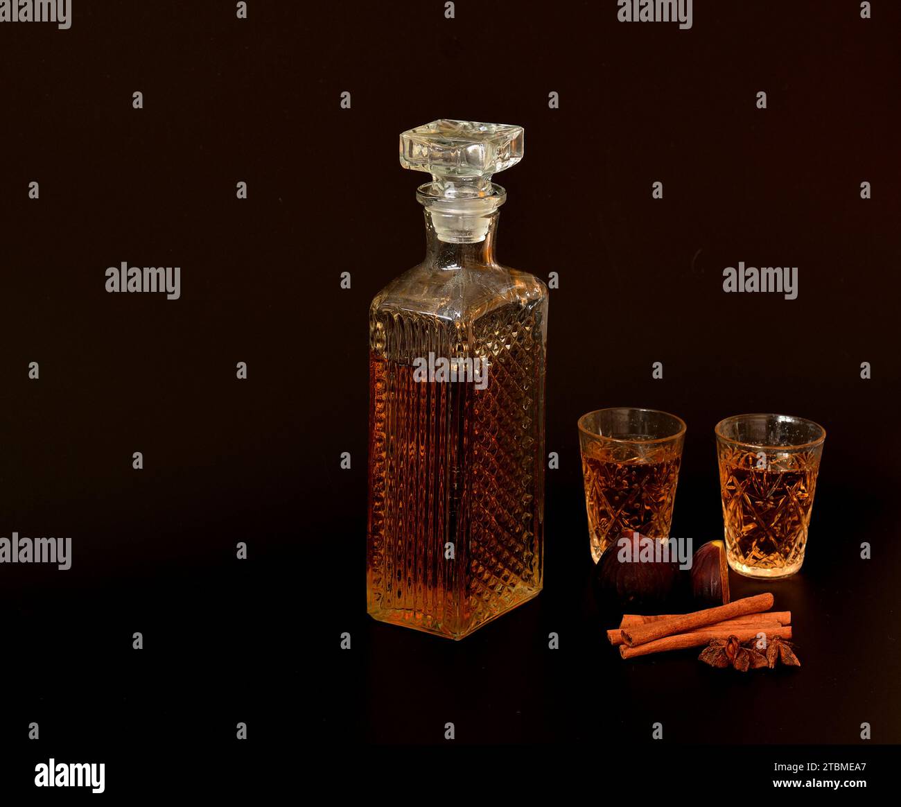 Fig liqueur with cinnamon and anise on a black background, a crystal ...