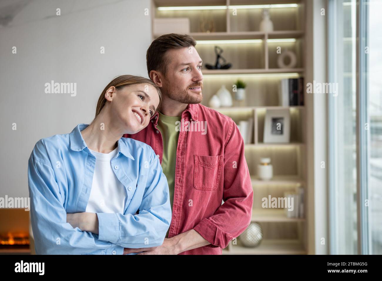 Romantic loving couple standing in front of window, dreaming, thinking ...