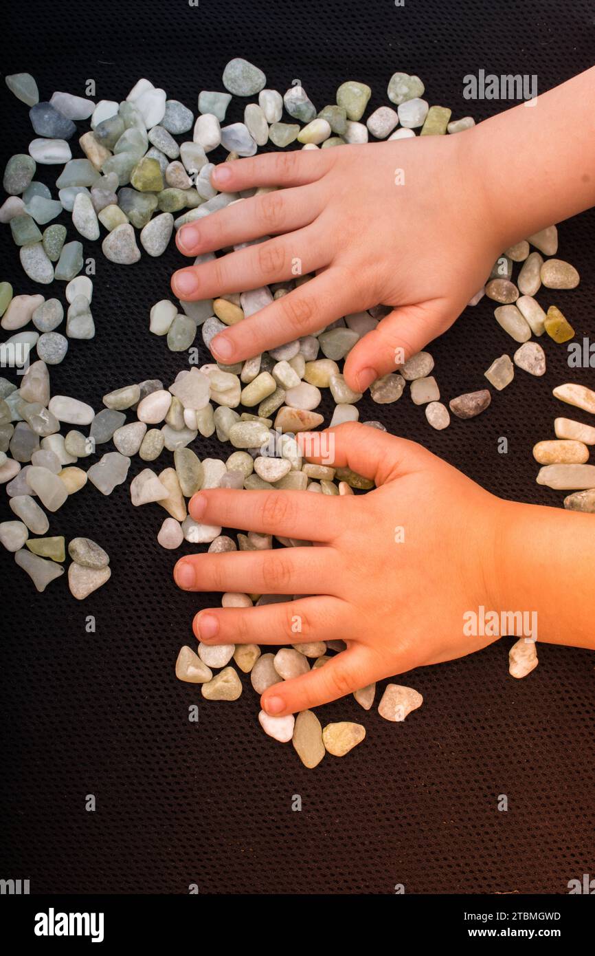 Clean stone pebbles gravels under hand on a black background Stock ...