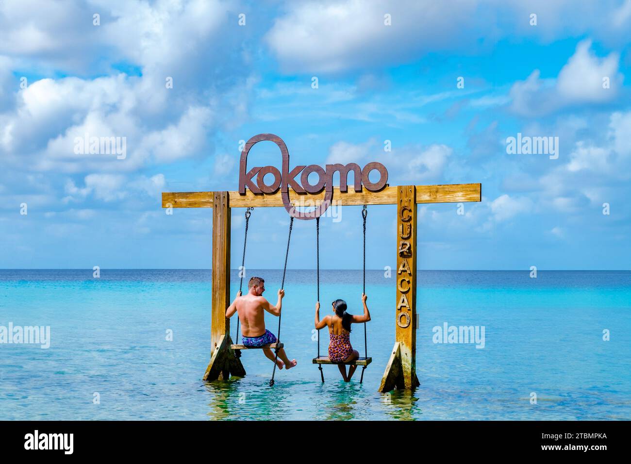 Couple of men and women at a swing in the ocean of Curacao Caribbean ...