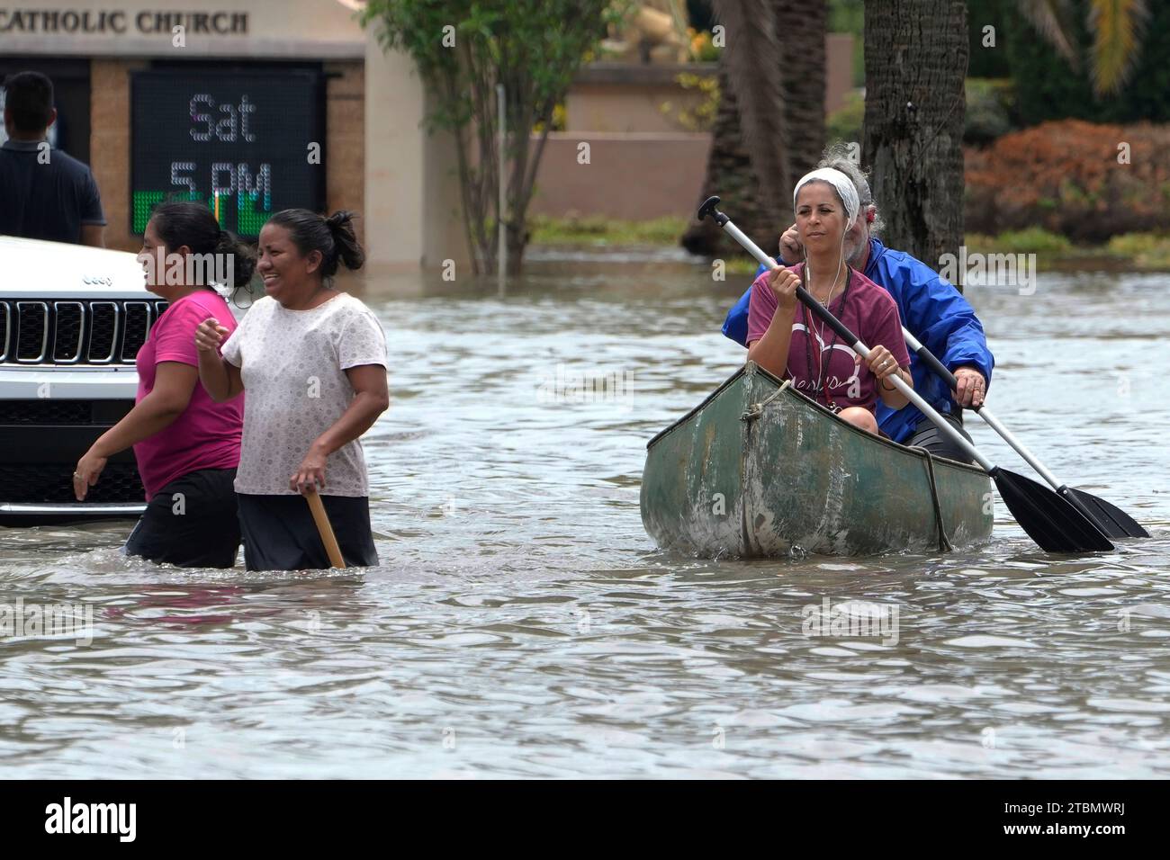 Residents paddle and walk along a flooded road Thursday, April 13, 2023 ...