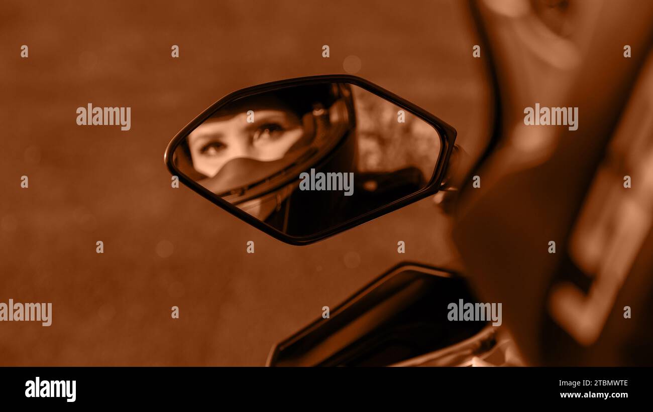 The girl on a motorcycle. Blurred reflection in mirror. Image toned in ...