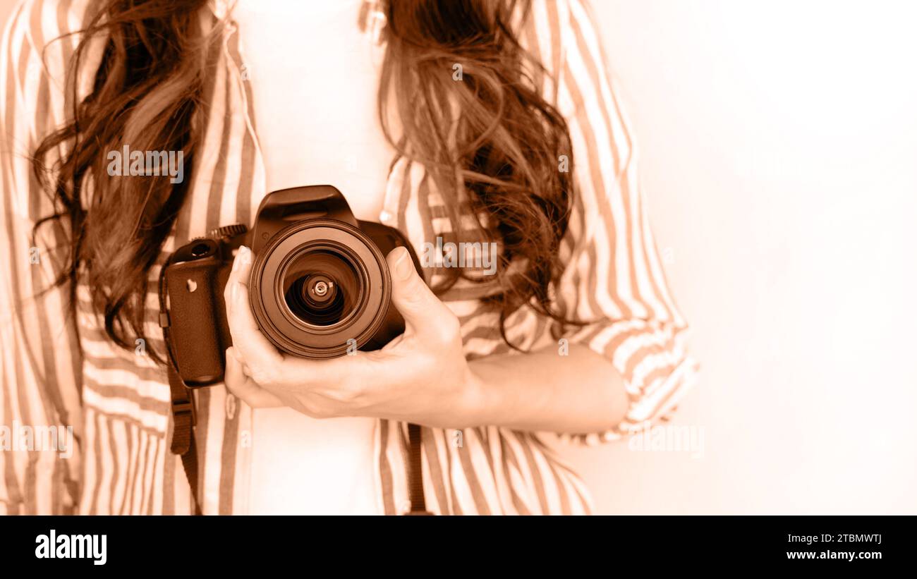 Photographer holding dslr camera. Image toned in Peach Fuzz color of ...