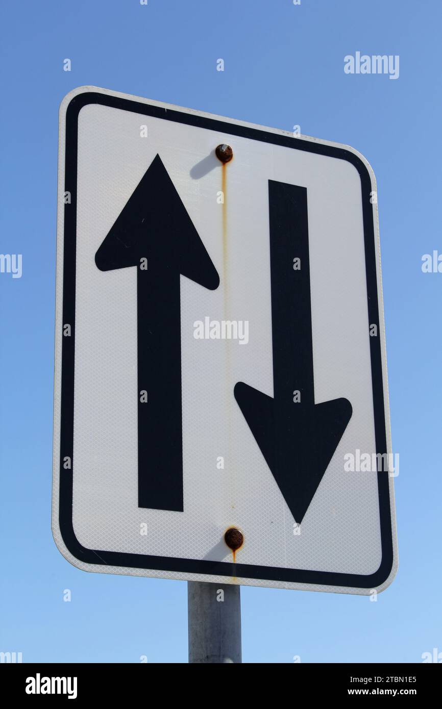 Two way street road sign against a blue sky background Stock Photo - Alamy