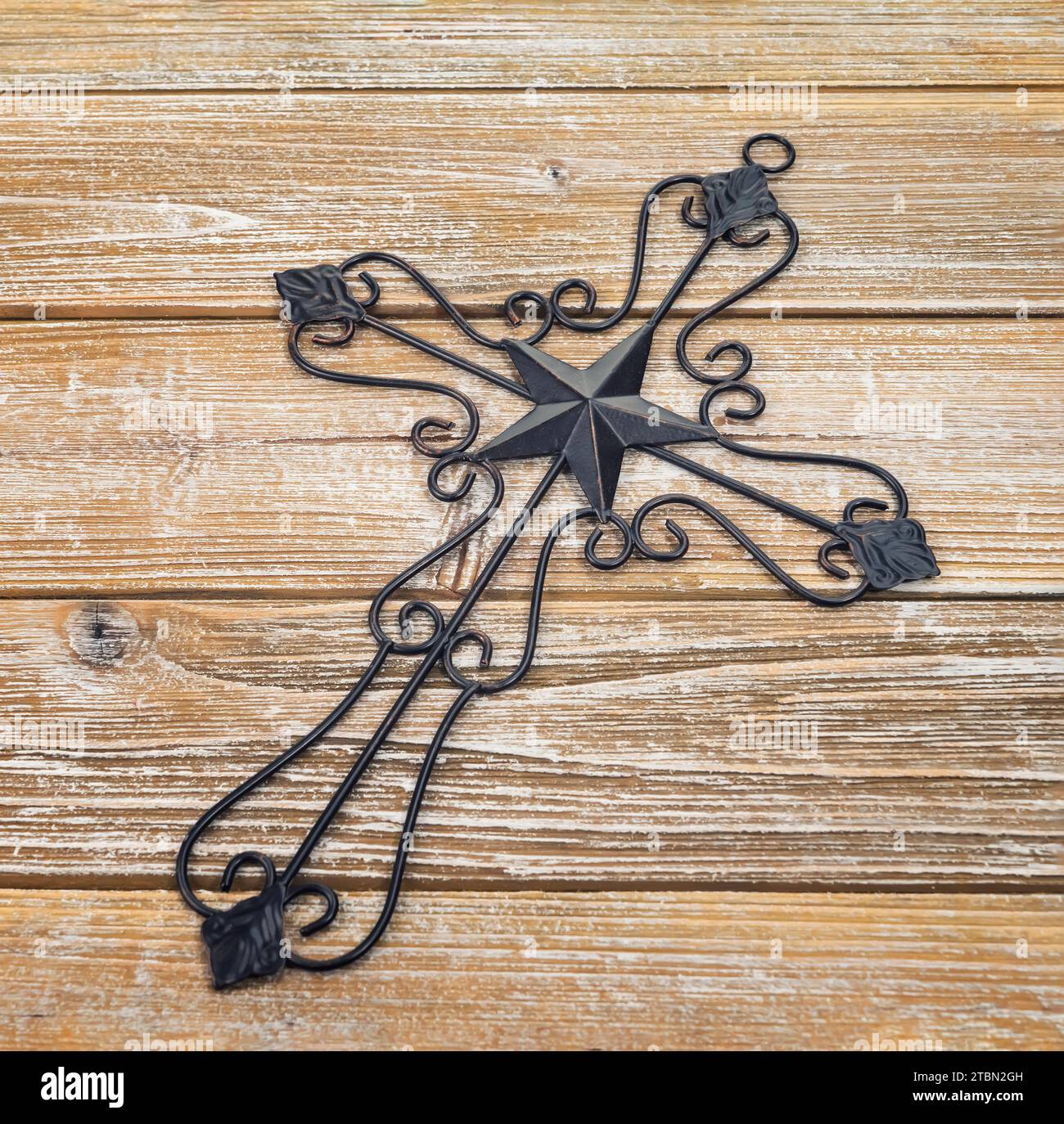 metal cross with scroll design hangs on wooden background Stock Photo ...
