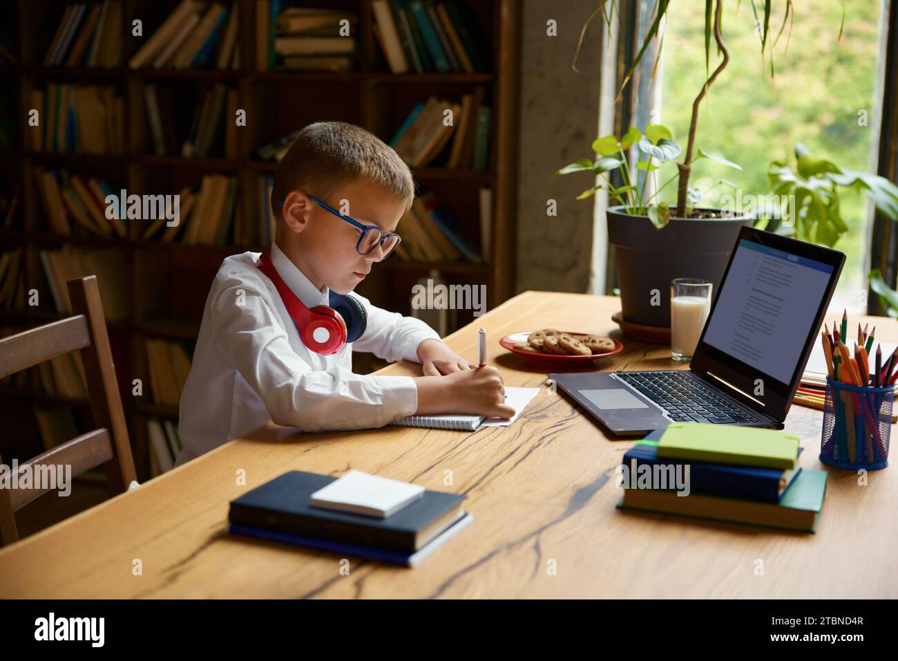 Little boy child studying at home table sitting front of computer ...